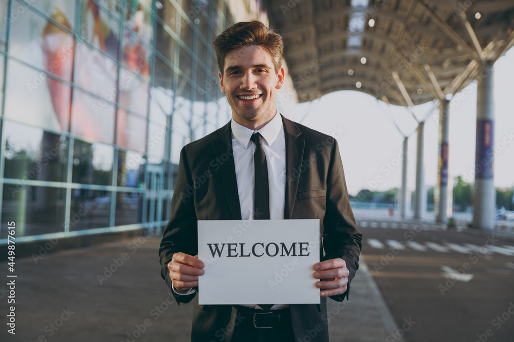 Friendly young satisfied traveler businessman man 20s in black suit ...