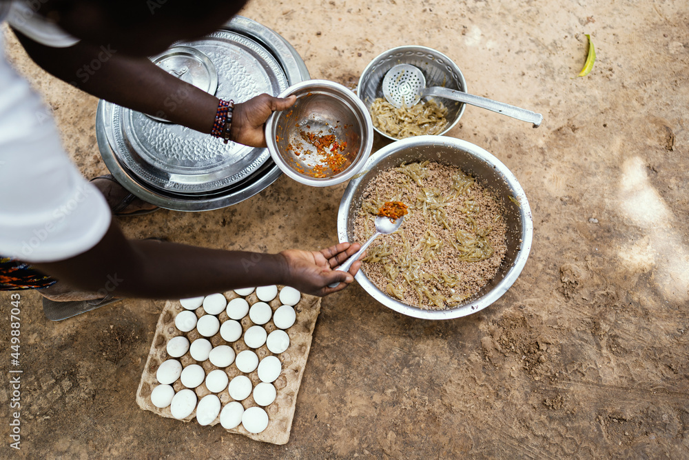 Black African cook adds spice to a simple dish she's preparing for her ...