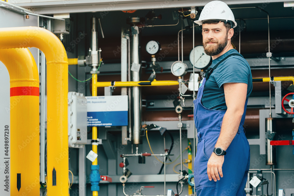 Portrait of a gas worker in a helmet and a working overalls against the ...