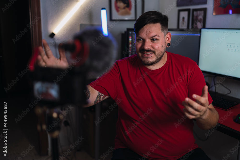 Chico joven gordo con camiseta roja grabando frente a una cámara en un ...