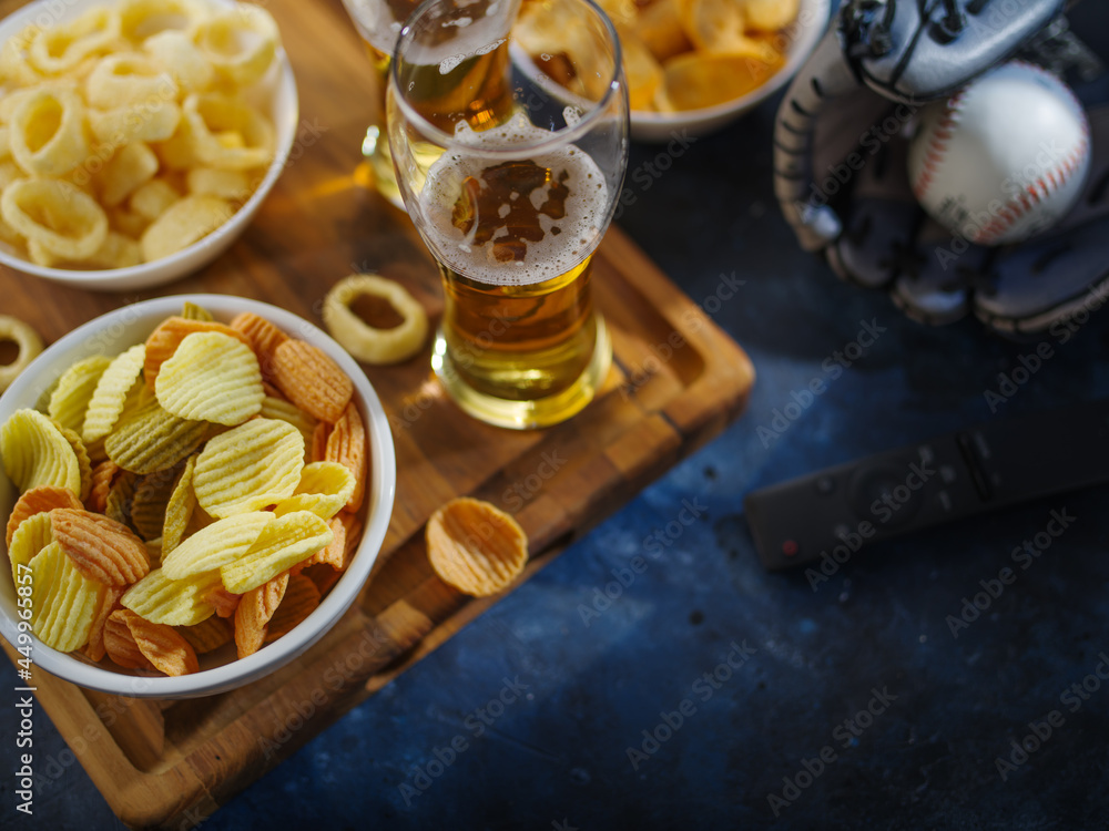 Baseball glove with ball, beer, chips, snacks, TV remote. Blue ...