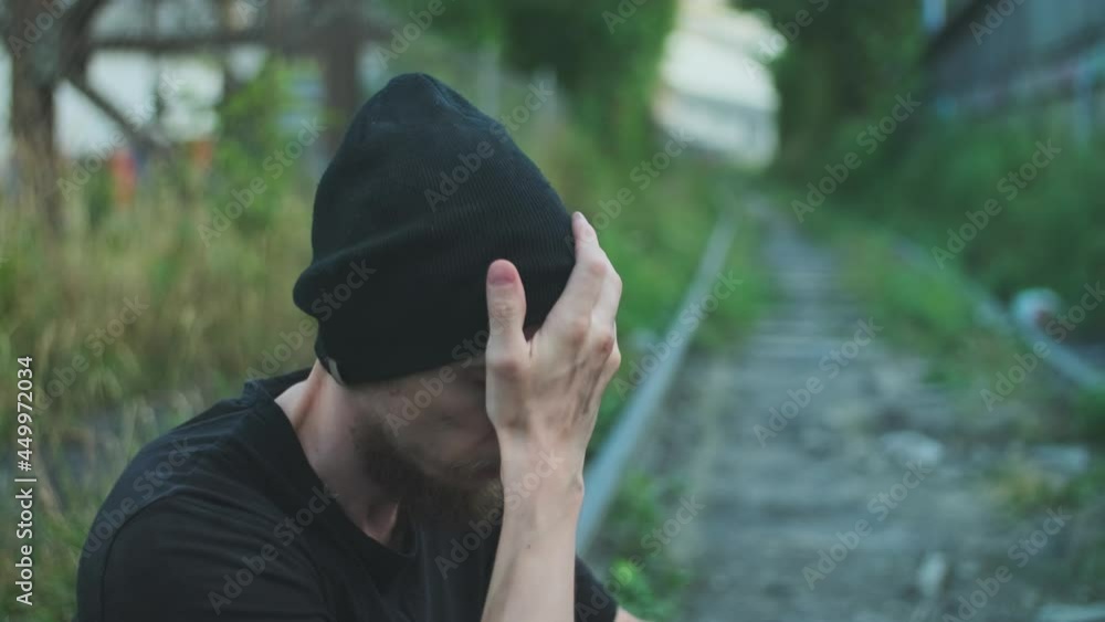 Homeless man with belongings gaunt of hunger ruffles his hat. broken ...