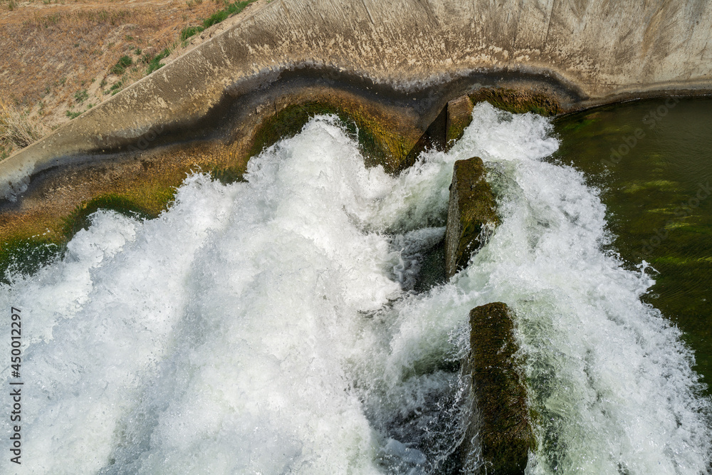 Water flows down a concrete channel from the Ringold Pond Dam toward ...