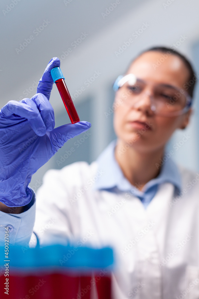 Specialist woman doctor looking at clinical vacutainer dna blood ...