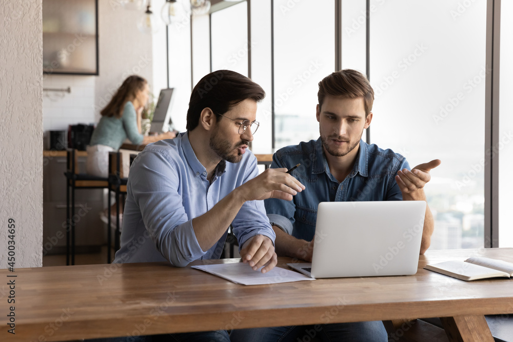 Office employees discussing project at laptop, sharing ideas. Mentor ...