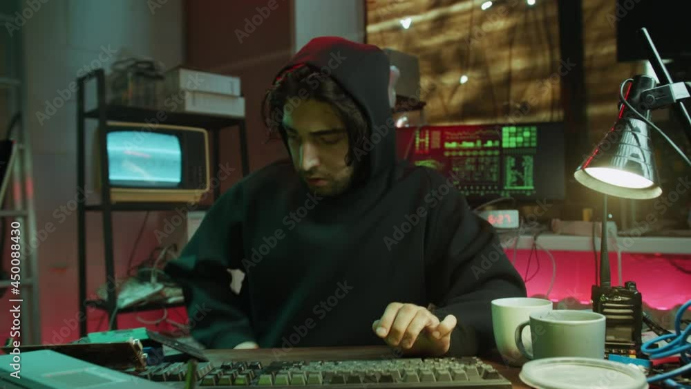Careful hacker wearing black hoodie, stealing information with usb from laptop, preparing to ...