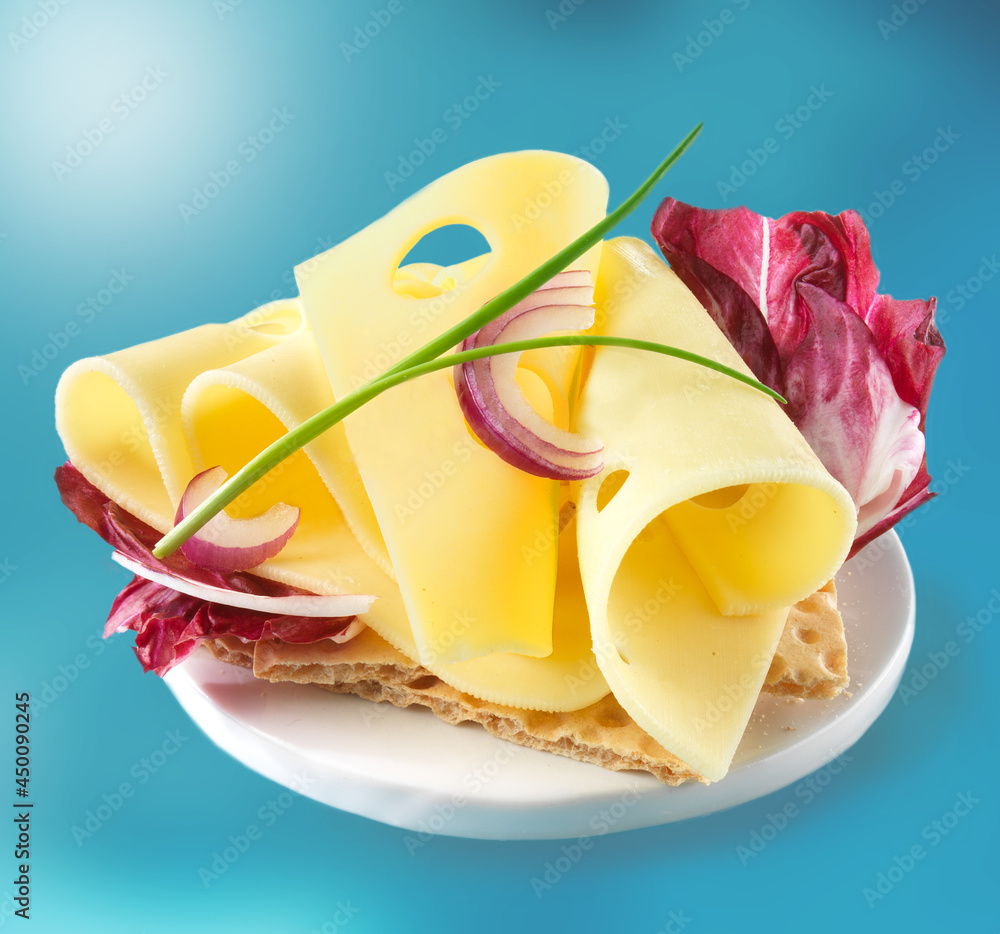 Maasdamer auf krossem Brot mit Gemüse angerichtet auf weissem Teller ...