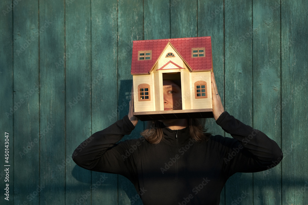 Female head inside tiny home. Woman holding toy house in front of her ...