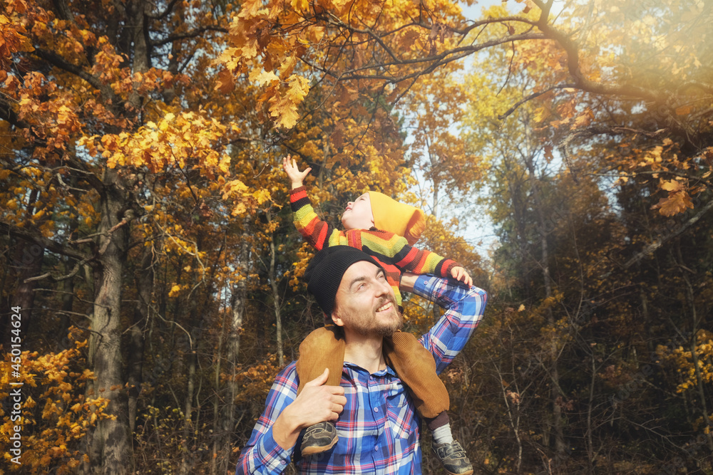 Cute little child boy sitting on his father's shoulders on background ...