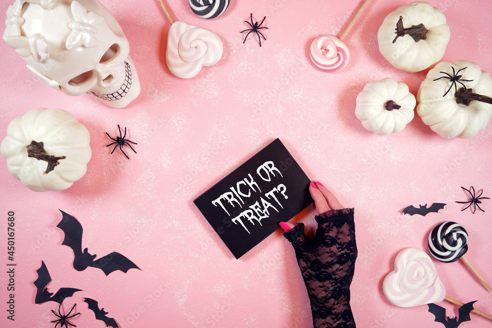Modern pink Halloween theme flatly background with woman's hand holding ...