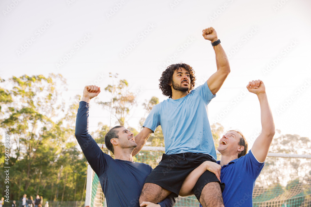 horizontal shot of two men carrying a man on their shoulders while ...