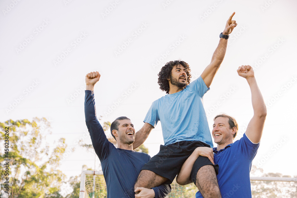 horizontal shot of two men carrying a man on their shoulders while ...