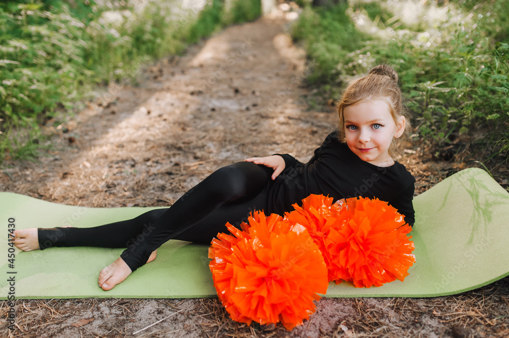 Foto de A tired, smiling girl, a child cheerleader in a black suit lies ...