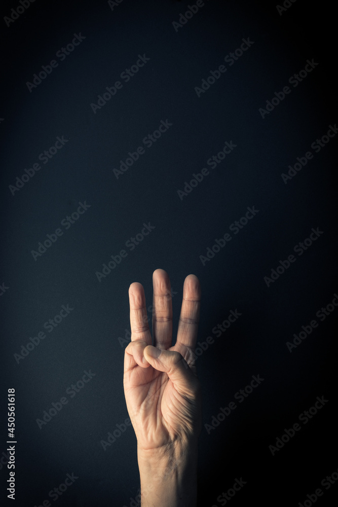 Colour image of hand demonstrating sign language number three against ...