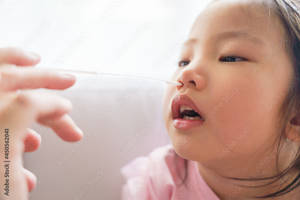 Adorable Asian girl kid getting swab test at home by her parent. Rapid ...