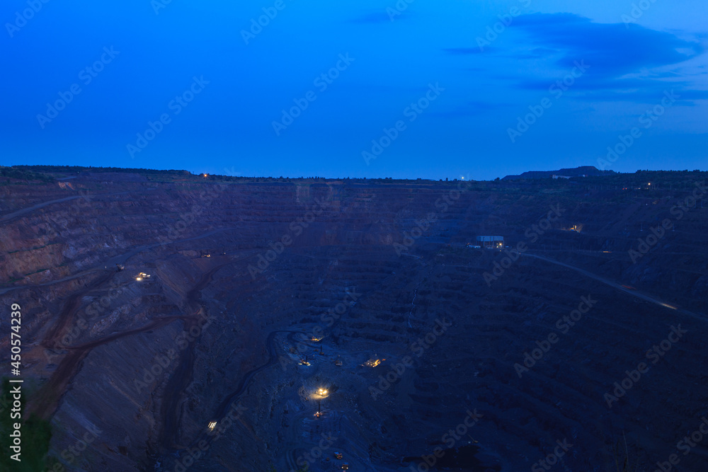 The process of ore extraction in the quarry at night. Heavy industry ...