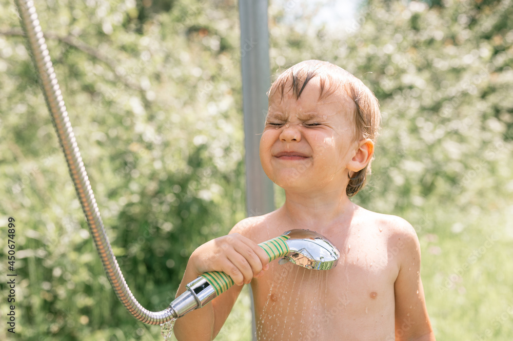 little four year old squint kid boy fun pours himself with cold water ...