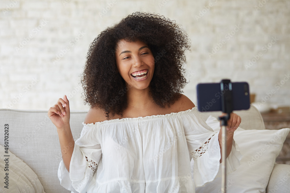Female black vlogger influencer sit at home speaking looking at camera ...
