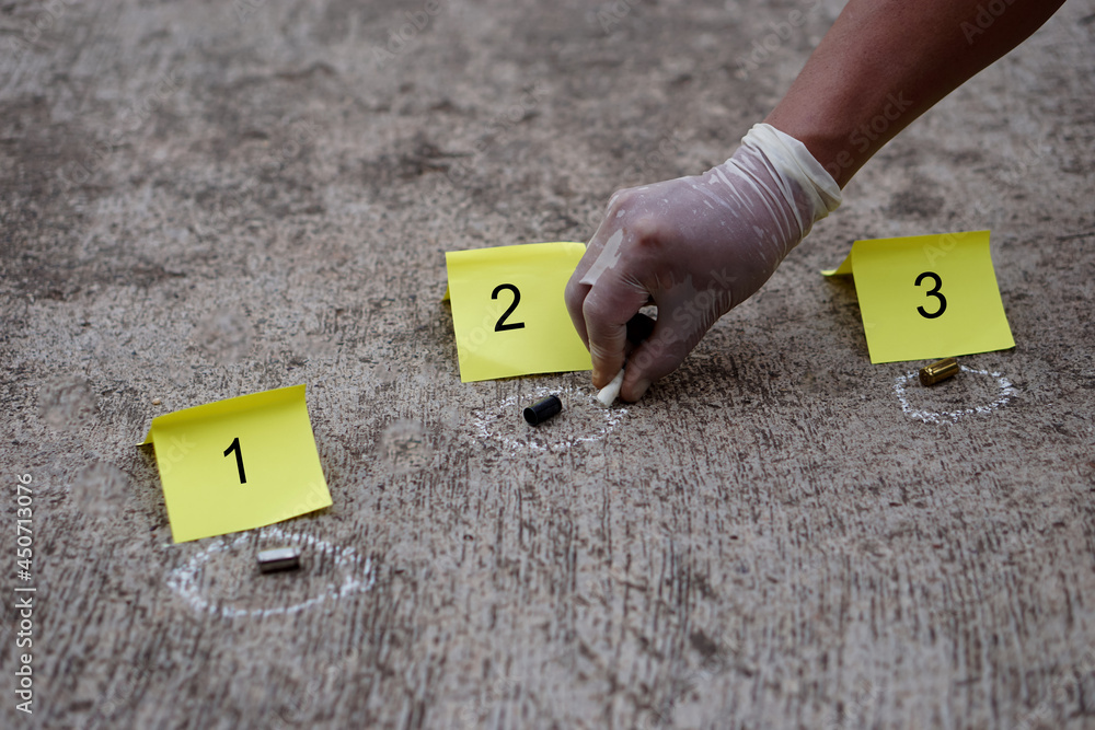 Concept : Crime scene. Hand is drawing circle around bullet shells on ...