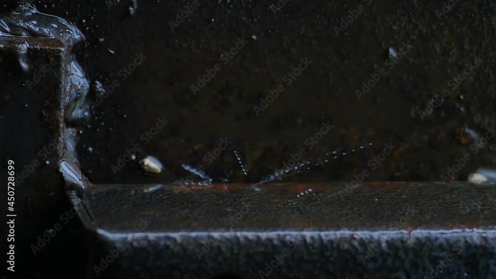 drops of water from heavy rain fall on metal surfaces in a dark place ...