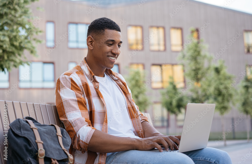 Handsome smiling computer programmer using laptop working online ...