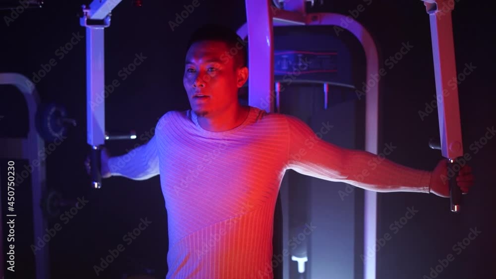 Asian man does butterfly chest exercise on machine. Chinese bodybuilder ...