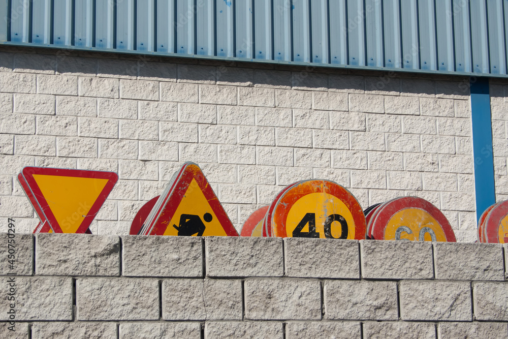 Road signs used for road repairs are stacked in a row at a construction ...