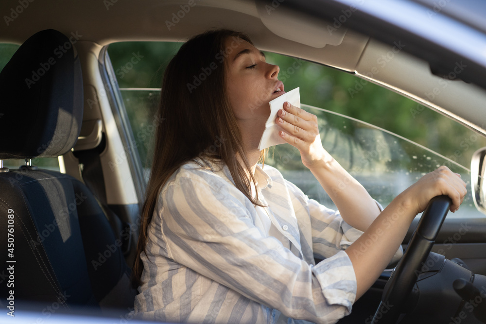 Young woman sweating tired of heat driving car hold tissue at face ...