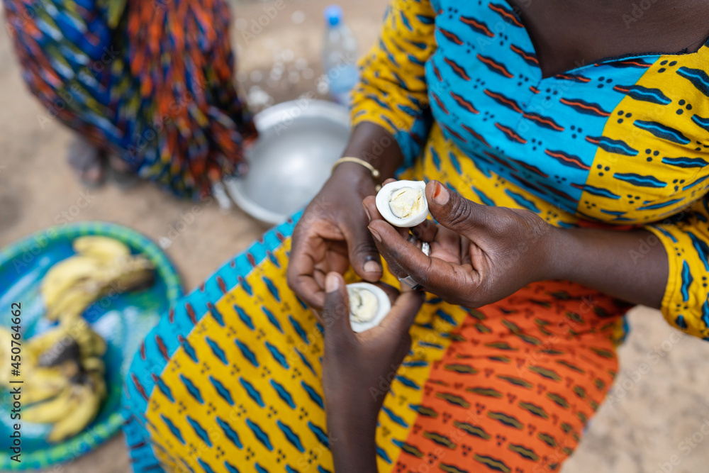 Fotka „Caring African woman in a colorful dress sitting on the floor in ...