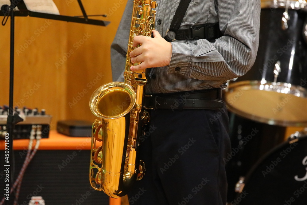 Boy kid playing big golden saxophone while practicing in class in ...