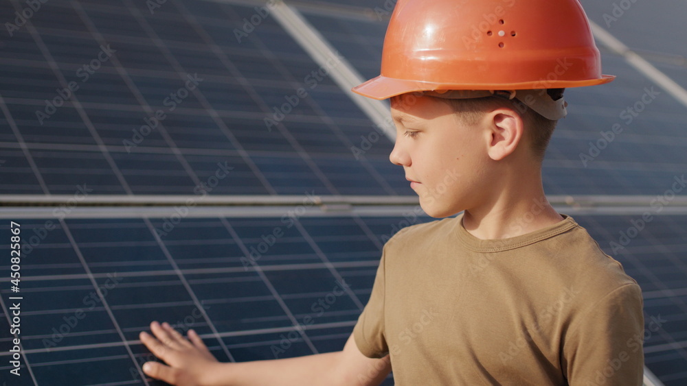 Little boy in a protective helmet at a solar power plant. The concept ...