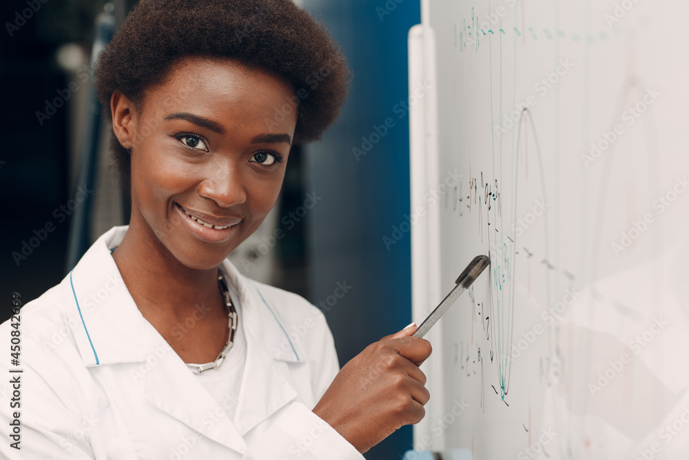 African American woman math univercity student writing on blackboard ...
