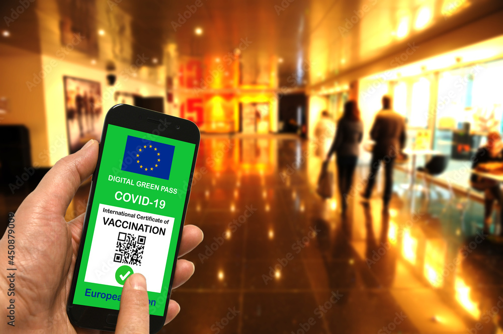 A man in a shopping mall holds a smartphone with the European Union ...