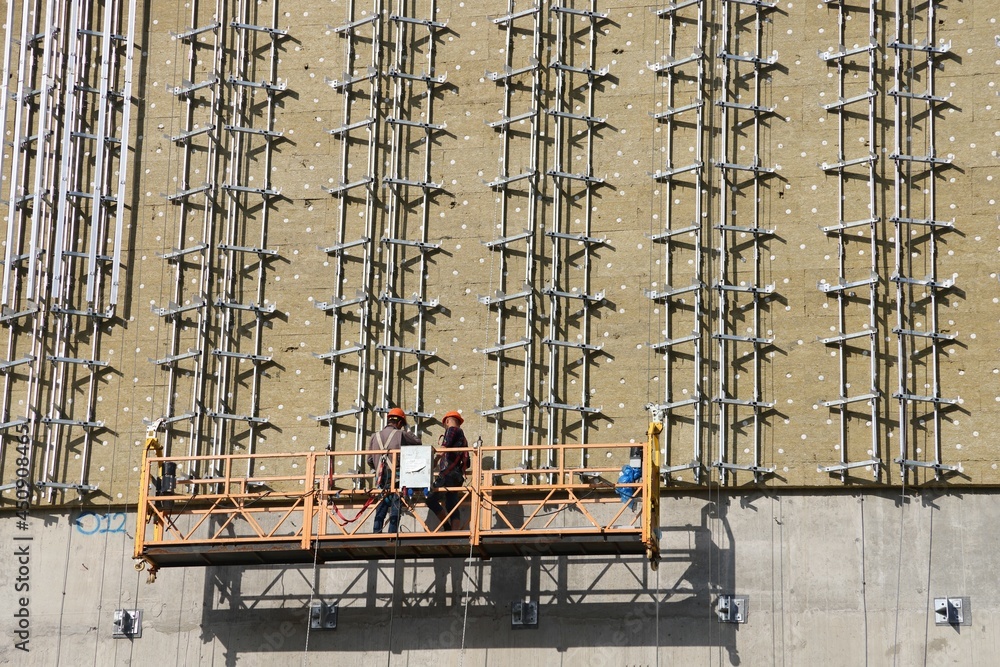 Construction cradle with workers on the wall of a building under ...