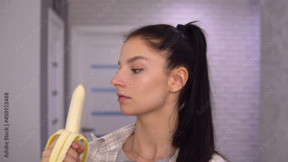 Young woman peeling banana, biting. Eating organic fruit, healthy ...