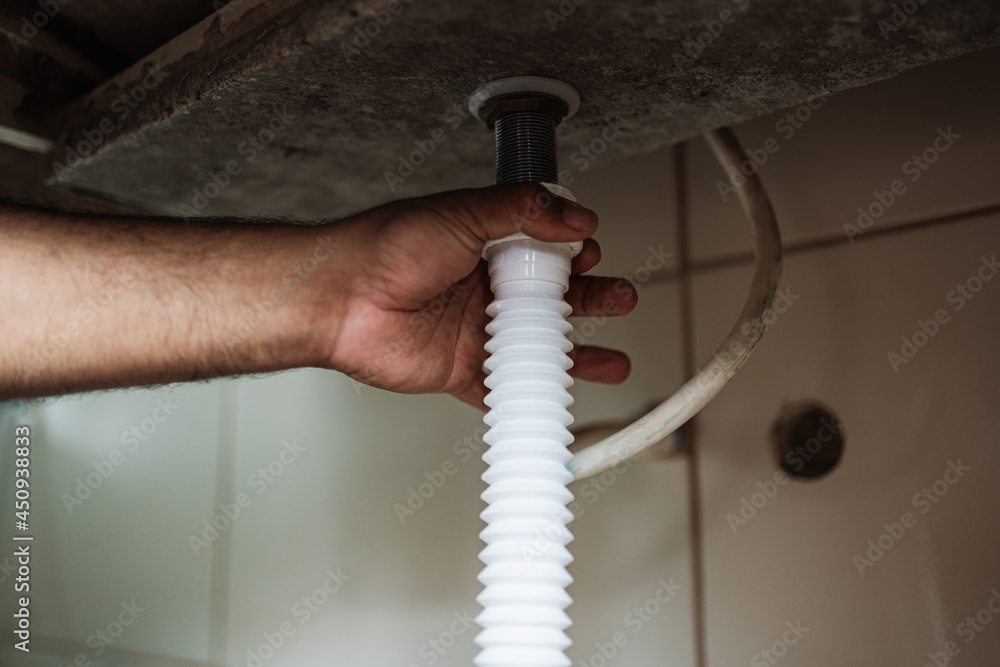 Plumber installs a siphon pipe on the kitchen sink. Refurbishment in ...