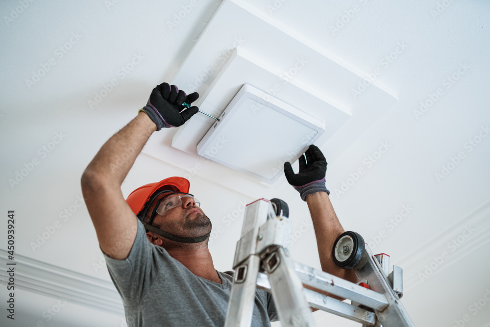 Latino electrician installing a led light on the ceiling. Stock Photo ...
