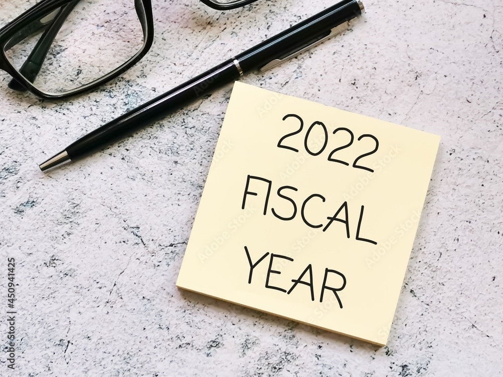 Text 2022 fiscal year written on sticky note with a pen and eye glasses ...