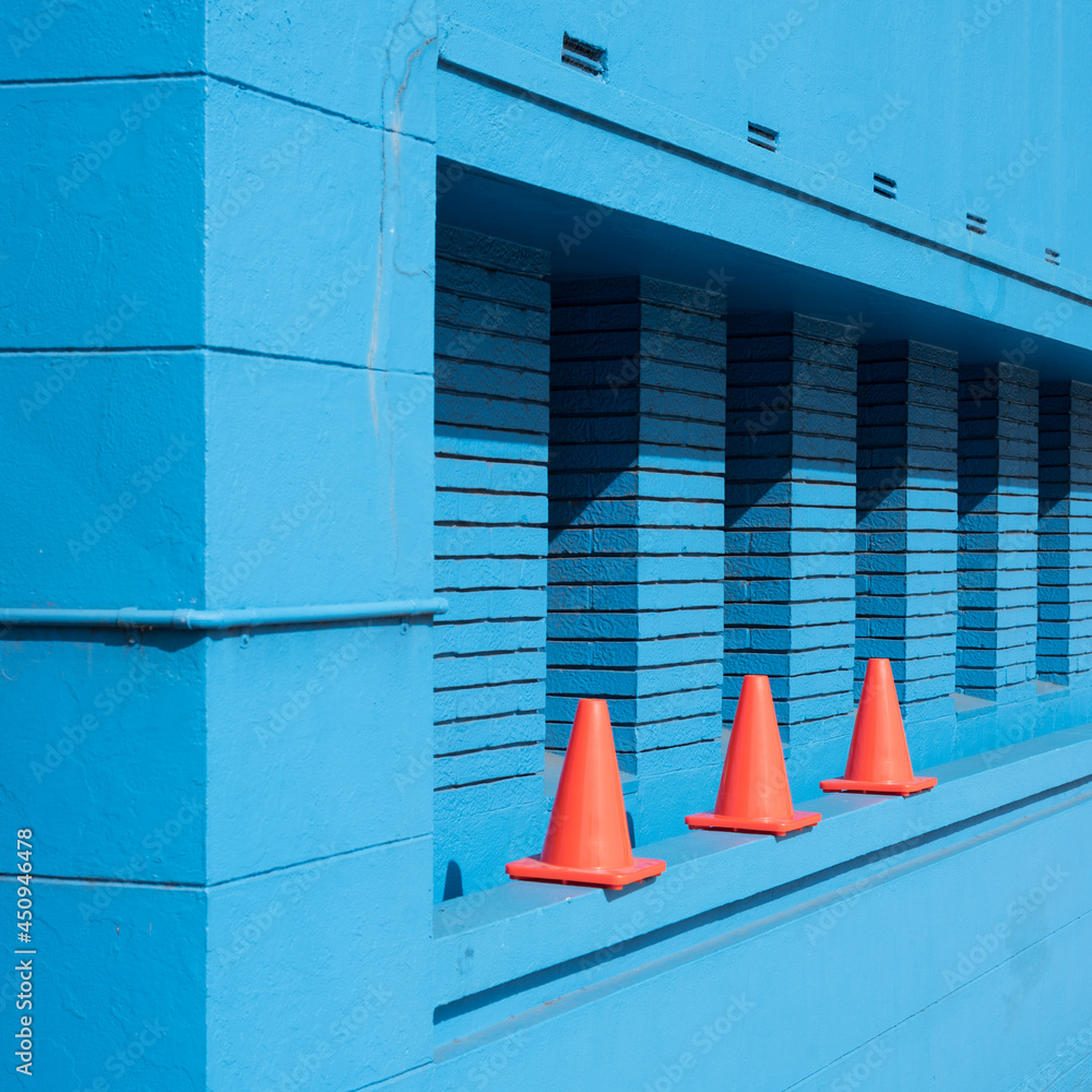 Orange traffic cones and a blue brick wall Stock Photo | Adobe Stock