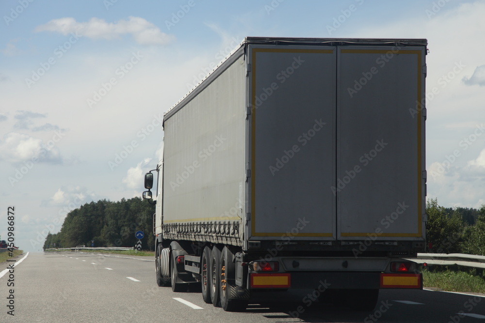 One European awning van semi truck back side close-up view drive on the ...
