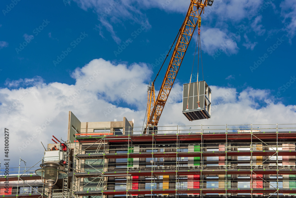Crane lifting a wooden building module to its position in the structure ...