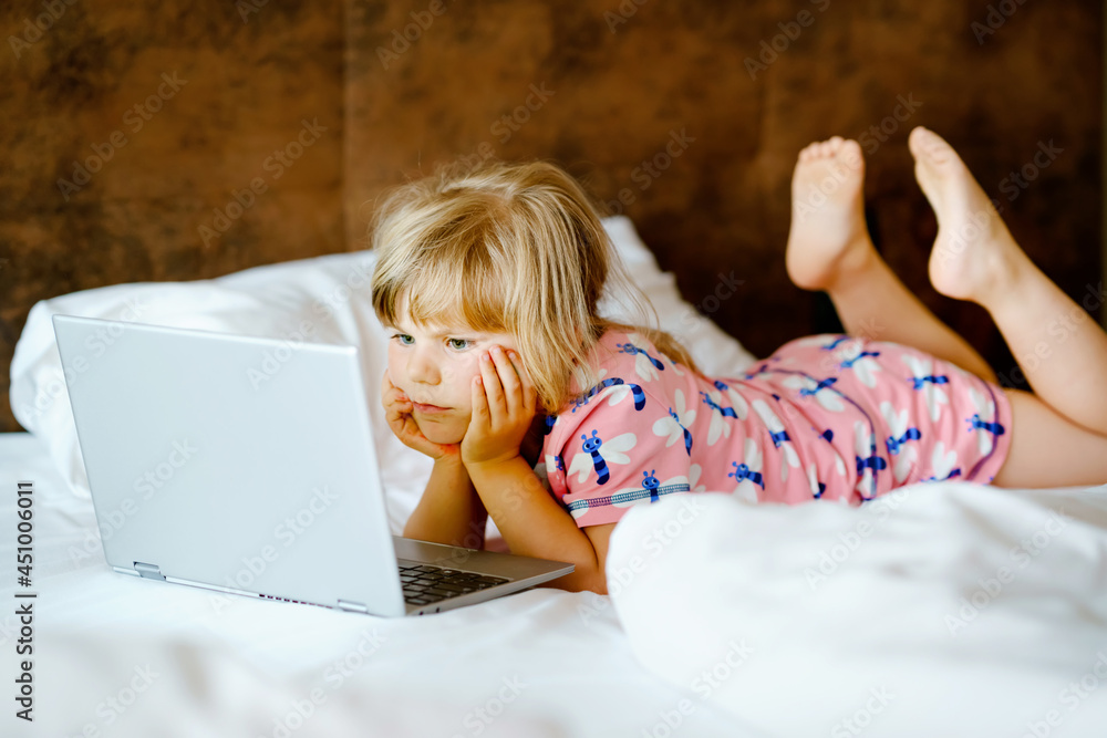 Preschool girl watching videos on laptop, notebook,in bed on clean ...