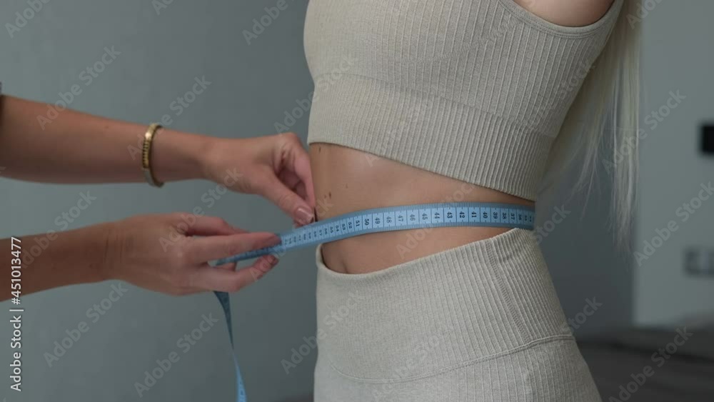 Fit woman measuring waist. Young female measuring body using tape ...