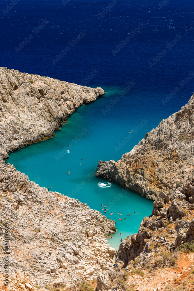 Small sandy beach with turquoise ocean hidden between tall cliffs in a ...