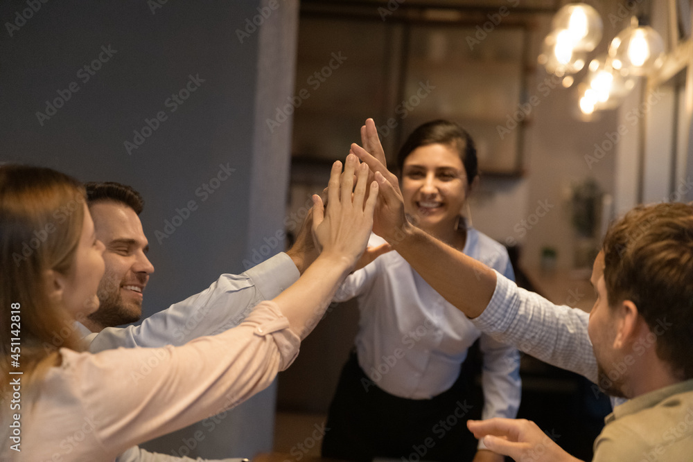 Excited diverse colleagues giving high five, showing unity finish ...