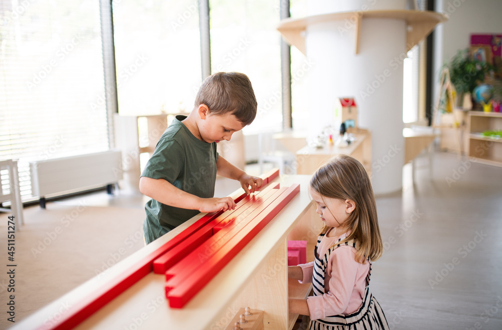 Group of small nursery school children playing indoors in classroom ...