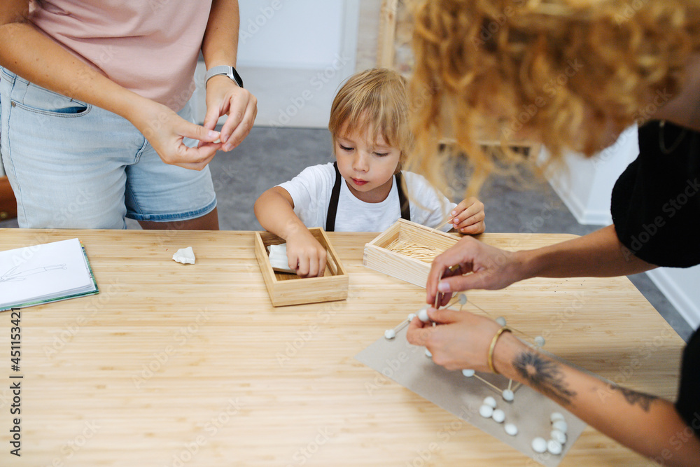 Fotka „Teachers helping boy to build 3d shapes from plasticine and ...