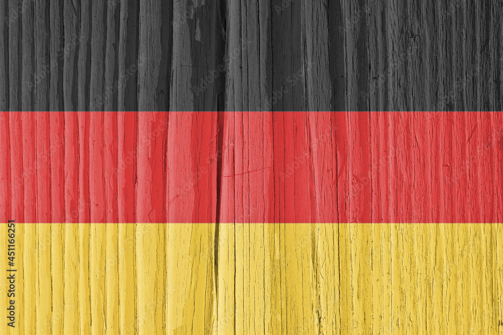 The flag of Germany on dry cracked wooden surface. It seems to flutter ...