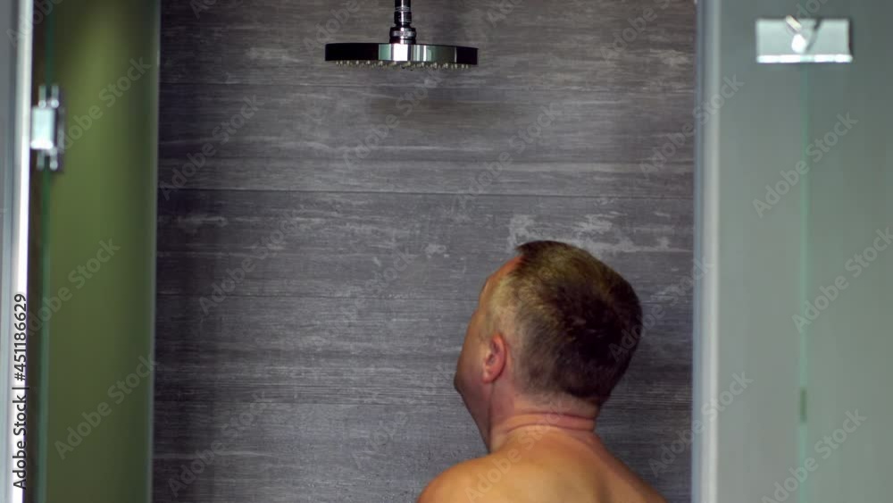 Man entering an indoor shower cubicle in a bathroom ready for his ...