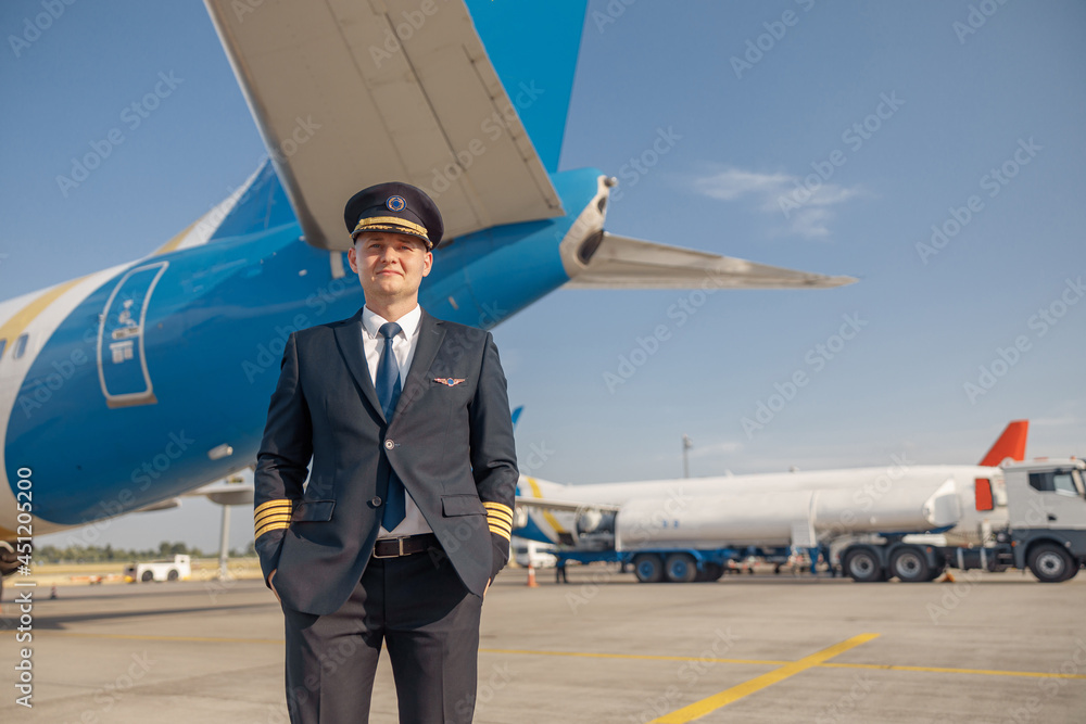 Professional pilot in uniform looking at camera, standing in front of ...